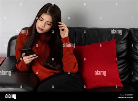 Portrait Of Pretty Young Indian Girl Sitting On A Couch And Holding