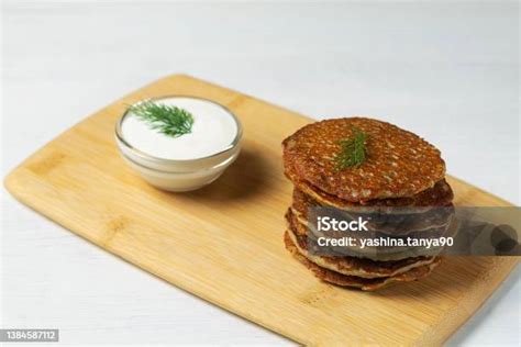 구운 감자 팬케이크와 화이트 사워 크림 도마에 녹색 허브가 있습니다 벨라루스 요리 복사 공간이있는 흰색 배경에 감자 팬케이크 0