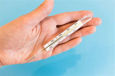 닫기 최대 전통적인 손잡고 체온을 측정 하기 위한 온도계 온도계를 바라보는 여자의 근접 촬영 샷입니다 여자는 온도 측정합니다 온도계에 초점 얕은 깊이 필드 감기와 독감에