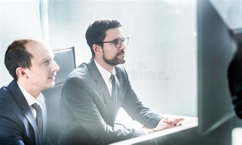 rear view of stock trader analyzing data at multiple computer screens