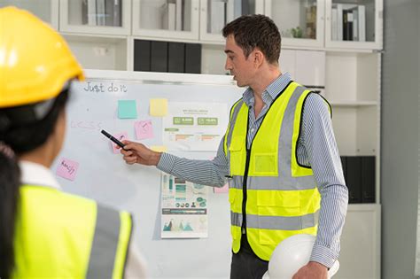 엔지니어 리더 맨 프리젠 테이션 프로젝트 및 전략 계획은 건설 현장 사무실의 회의실에서 사업가 기업과 함께 화이트 보드에서