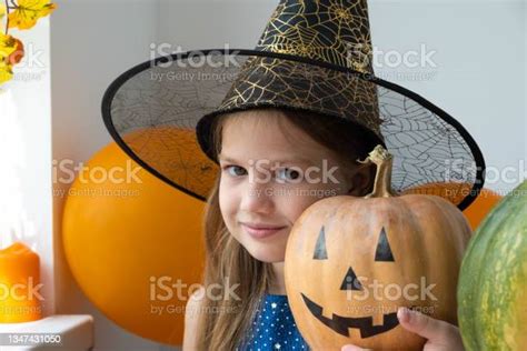 잭 오 랜턴 얼굴과 호박을 들고 마녀 의상을 입은 어린 소녀의 초상화 집에서 할로윈을 준비하는 검은 모자를 쓴 아이 가족 휴가