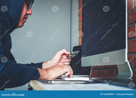 Dangerous Hooded Hacker Using Credit Card Typing Bad Data Into Computer Online System And