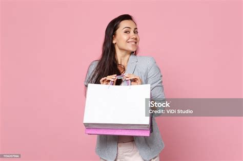 분홍색 파스텔 배경에 고립 된 쇼핑 후 구매와 패키지 가방을 들고 옆으로 찾고 줄무늬 재킷에 웃는 젊은 여자 사람들은 진심으로 감정 라이프 스타일 개념입니다 복사 공간을