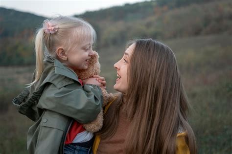 Junge Mutter mit Tochter im Arm lacht und hat Spaß in der Natur an einem Herbsttag Porträt eines