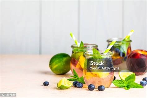 블루베리와 복숭아는 물방울과 함께 항아리에 물 칵테일 레모네이드 또는 차를 주입합니다 블루베리 라임 복숭아 민트가 있는 여름