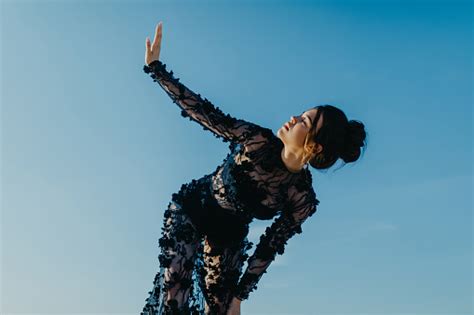 레이스 블랙 드레스를 입은 여성이 푸른 하늘을 배경으로 서 있다 20 29세에 대한 스톡 사진 및 기타 이미지 20 29세 가냘픈 가리기 Istock