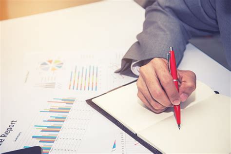 펜을 들고 사무실에서 비즈니스 차트를 분석 하는 노트북에 뭔가 쓰는 비즈니스 남자 손 계획에 대한 스톡 사진 및 기타 이미지