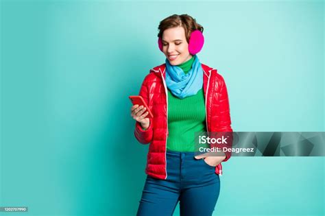 얘들 아 난 이미 여기 있어요 사진 예쁜 여자 채팅 전화 쓰기 친구 대기 회의 착용 캐주얼 빨간 코트 스카프 핑크 귀 커버 스웨터 바지 고립 된 청록색 배경 갈색 머리에