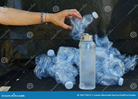 Hand With Glass Water Bottle In Front Of Stack Of Plastic Bottles Sustainable Alternatives