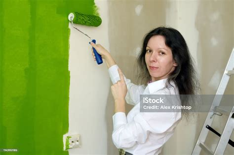 웃는 예쁜 젊은 여자의 초상화 흰색 셔츠 그림 녹색 인테리어 벽을 새 집에서 롤러와 그녀의 작품을 가리키는 Diy에 대한 스톡 사진 및 기타 이미지 Istock