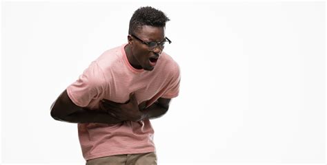 때문에 위장에 손으로 분홍색 티셔츠를 입고 젊은 아프리카계 미국인 남자가 메스꺼움 몸이 느끼는 고통 스러운 질병 통증 개념입니다 T 셔츠에 대한 스톡 사진 및 기타 이미지