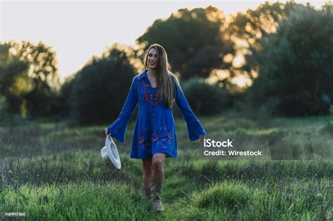 파란 드레스를 입고 햇볕이 내리쬐는 초원에 서 있는 모자를 쓴 예쁜 백인 젊은 여성 드레스에 대한 스톡 사진 및 기타 이미지 드레스 들 명랑한 Istock