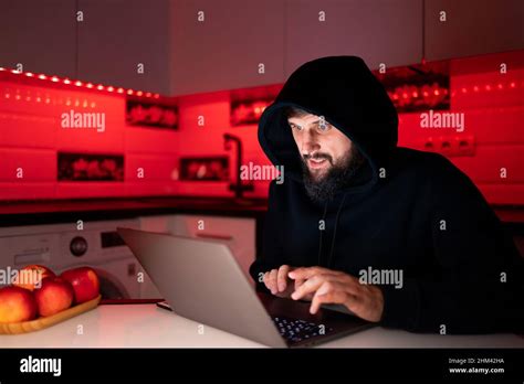 A Hacker In A Black Hoodie Is Sitting At A Laptop Hacking The Internet