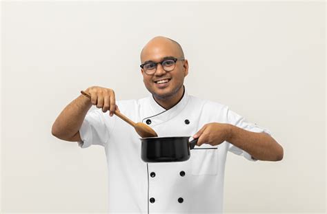 부엌에서 요리하는 제복을 입은 젊은 잘 생긴 아시아 남자 요리사는 부엌에서 요리하는 래들과 냄비기구를 들고 고립 된 배경에서 다양한 제스처 액션을 취합니다 인도 남자 직업