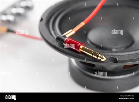 Close Up Red Aux Auxiliary Cable With Male Jack With Speaker In The Background Cable For