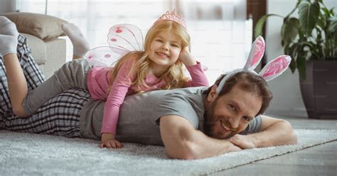 재미있는 게임 즐거운 남자의 초상화는 아이를 등에 업고 바닥에 누워 있다 그는 카메라를 바라보며 웃고 있다 소녀는 요정