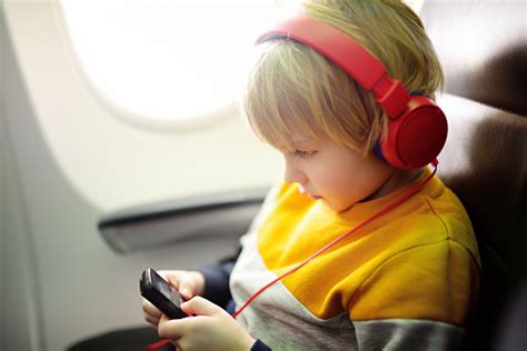 비행기로 여행하는 귀여운 어린 소년 비행 중에 플레이어를 사용하여 음악이나 오디오 북을 듣는 어린이 비행기 탑승 어린이를위한 엔터테인먼트 6 7 살에 대한 스톡 사진 및