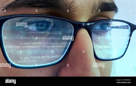 A Man Working On Computer Looking At Programming Code Reflecting In His