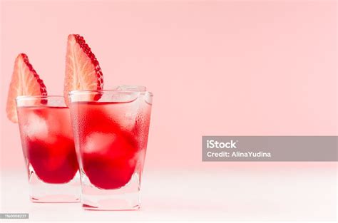 흰색 나무 판에 파스텔 핑크 색상의 트렌디 한 현대 바 인테리어에 딸기 조각 얼음 조각 두 샷 안경에 밝은 빨간 알코올 샷 0