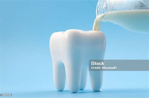 구강 건강 공동 예방 및 칼슘이 풍부한 음료는 푸른 배경에 고립 된 열이 많은 치아에 우유를 붓는 유리 병으로 강한 치아