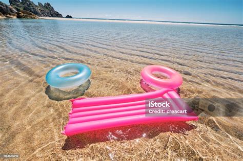 완벽한 6 월 날 콘월 의 페던 보더 비치 의 맑은 얕은 바다에서 웃는 얼굴 모양으로 배열 된 두 개의 고무 링과 릴로 0명에