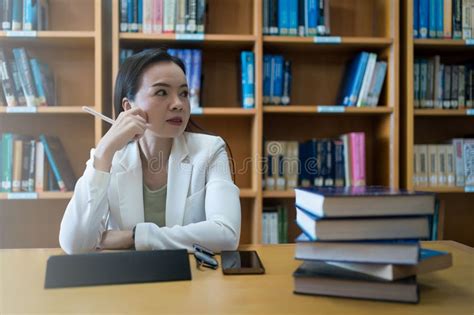 Southeast Asian Female Lecturer Sits At A Small Table Working At The Library Stock Image