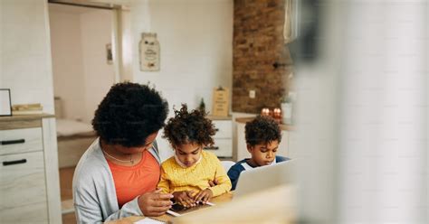 아프리카계 미국인 어머니는 집에서 일하는 동안 딸과 이야기합니다 작은 소년이 그들 옆에 앉아 있습니다 공간을 복사합니다