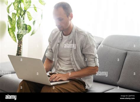 Young Male Tech User Relaxing On Sofa Holding Laptop Computer Mock Up