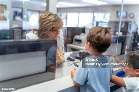 친절한 접수 원이 사무실 프론트 데스크에서 두 명의 어린 소년을 맞이합니다 교육에 대한 스톡 사진 및 기타 이미지 교육