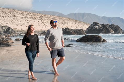 Premium Photo Young Latin Couple Walking Along The Shore Of The Beach