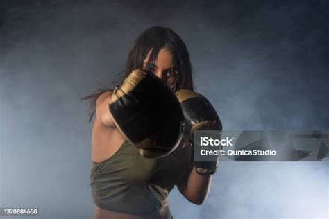권투 장갑을 들고 포즈를 취하고 연기가 자욱한 배경으로 카메라를 바라보는 여성 복서의 클로즈업 초상화 18 19세에 대한 스톡