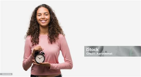 젊은 스페인 여 자가 서 이빨을 보여주는 자신감 미소로 웃 고 행복 한 얼굴로 알람 시계를 들고 건강한 생활방식에 대한 스톡 사진 및 기타 이미지 Istock