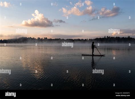 A Beautiful View Of A Man On A Puddle Board On A Sunset Scene