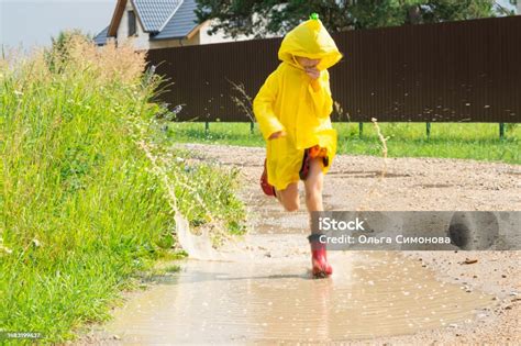 빨간 고무 부츠와 노란 비옷을 입은 소녀가 마을에 비가 내린 후 웅덩이를 통과합니다 여름 시간 자유 어린 시절 4 5세에 대한 스톡 사진 및 기타 이미지 Istock
