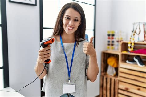 Premium Photo Young Brunette Woman Working At Retail Store Holding Barcode Reader Device