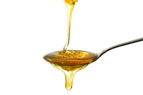 Premium Photo Closeup Of Appetizing Honey Flowing On A Spoon Isolated On White Background