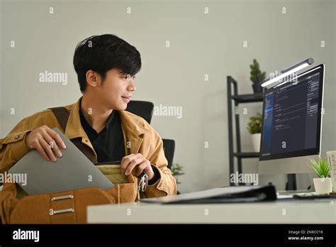 Asian Male Programmer Sitting Front Of Computers With Coded Data On