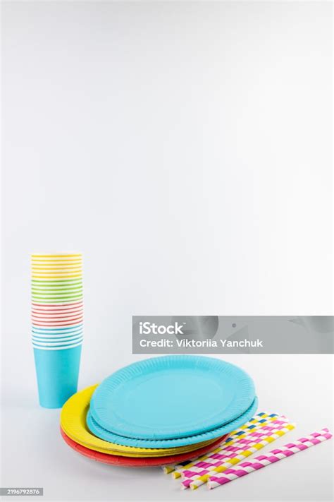 흰색 배경에는 노란색 빨간색 파란색의 종이컵 3 개가 있으며 일치하는 종이 접시와 빨대가 있으며 일회용 식기 표준 피크닉 세트가 있습니다 0명에 대한 스톡 사진 및 기타