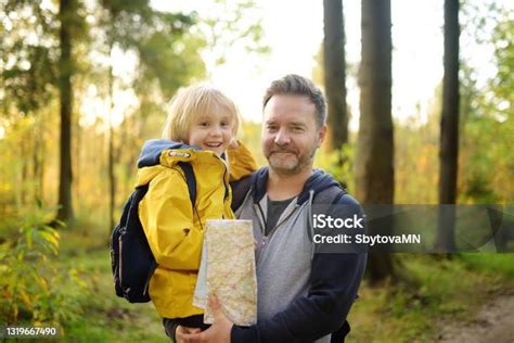 학생과 성숙한 아버지는 함께 하이킹과 자연을 탐험 아빠와 함께 소년은 햇볕이 잘 드는 숲에서 함께 양질의 가족 시간을 보낸다 아이들을위한 모험 스카우트 오리엔티어링 및