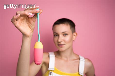 Hipster woman holding sex toy with antenna at outstretched arm while posing 이미지