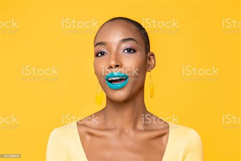 노란색 스튜디오 배경에서 고립 된 카메라를 보고 세련된 다채로운 메이크업으로 깜짝 놀란 젊은 아프리카 계 미국인 여성의 초상화를 닫습니다 35 39세에 대한 스톡 사진 및