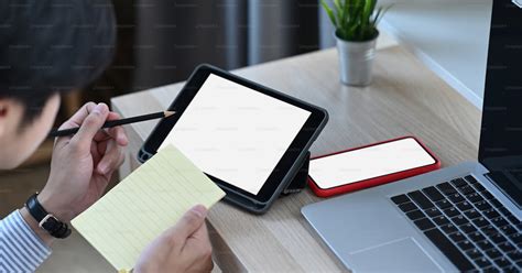 태블릿으로 작업하고 책상에서 개인 종이에 메모를 하는 남자의 잘린 샷 사진 Unsplash의 스마트폰 이미지