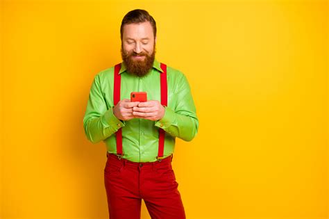 초상화 의 긍정적 인 쾌활한 아일랜드 남자 사용 휴대 전화 팔로우 블로그 게시물 댓글 피드백 착용 서스펜더 바지 위에 고립 된