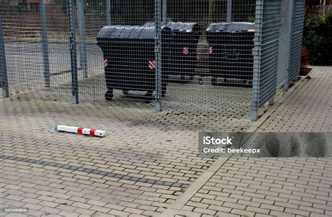 가정 쓰레기를 분류하기위한 컨테이너를 배치하기위한 마당 회색 문과 천공 된 금속 그리드의 절반 확장 된 금속 돌 와이어 바구니가