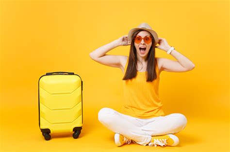 여행자 관광 여자 여름 캐주얼 옷 모자 가방 노란색 오렌지 배경에 격리와 앉아 여성 승객 주말도 주에 여행을 해외 여행 공기 비행 여행 개념 Unmanned