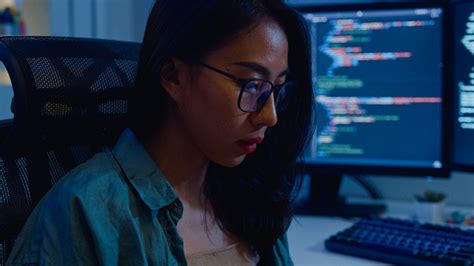 Young Asian Woman Software Developers Using Computer To Write Code Sitting At Desk With Multiple