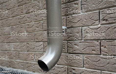 지붕 거터 설치 금속 비 배수구 다운 스푸트 브래킷으로 고정 된 다운 파이프 집 기초파이프 클립 가짜 돌 벽돌 패널타일 지하의 클로즈업 0명에 대한 스톡 사진 및 기타