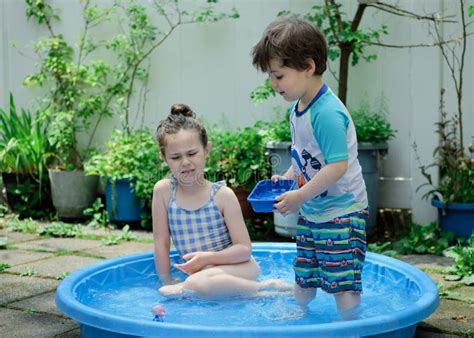 Brother And Sister Playing In A Shallow Pool In The Backyard Stock Photo Image Of Biracial