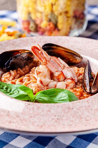 나폴리 요리 해산물 새우 홍합을 곁들인 이탈리아 리조또를 토마토 페이스트에 넣습니다 분홍색 접시에 레스토랑에서 요리를 제공합니다